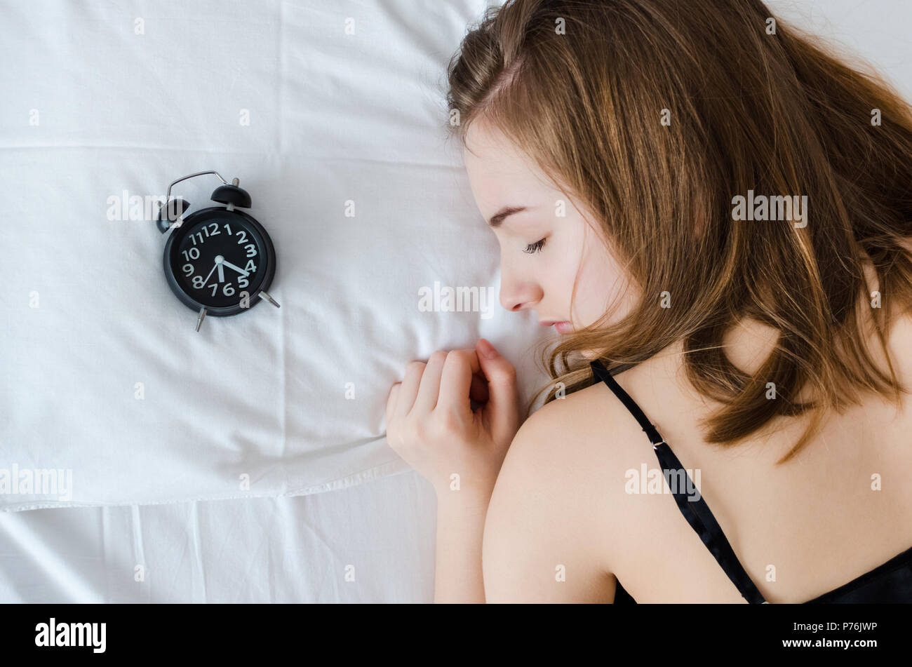 Young woman sleep with alarm clock on the pillow in the morning ...