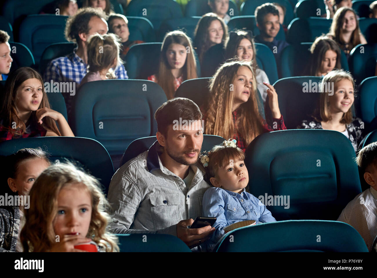 Spectators sitting in comfortable chairs in movie theatre and enjoying ...