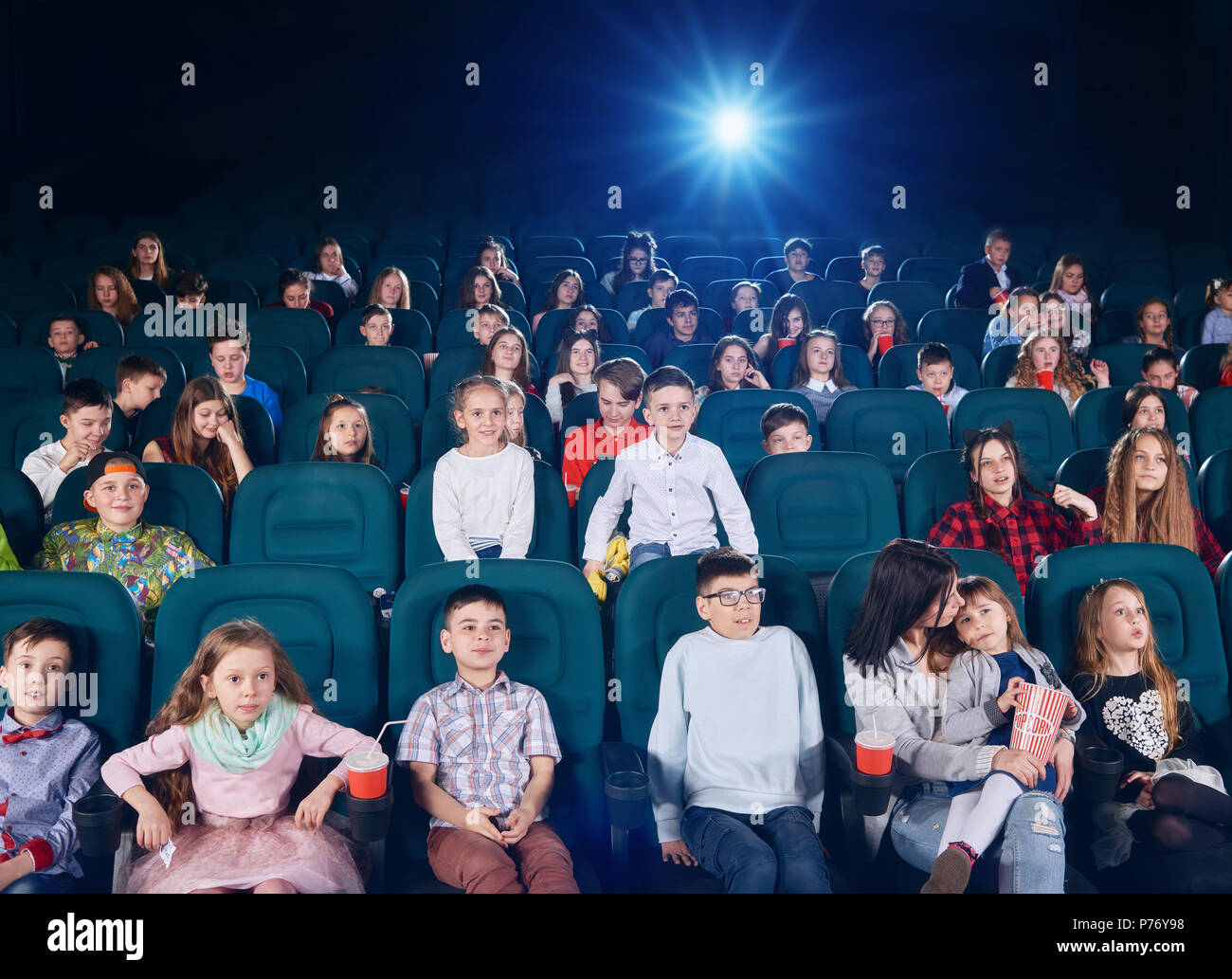 View of young spectators in modern cinema looking at screen and ...