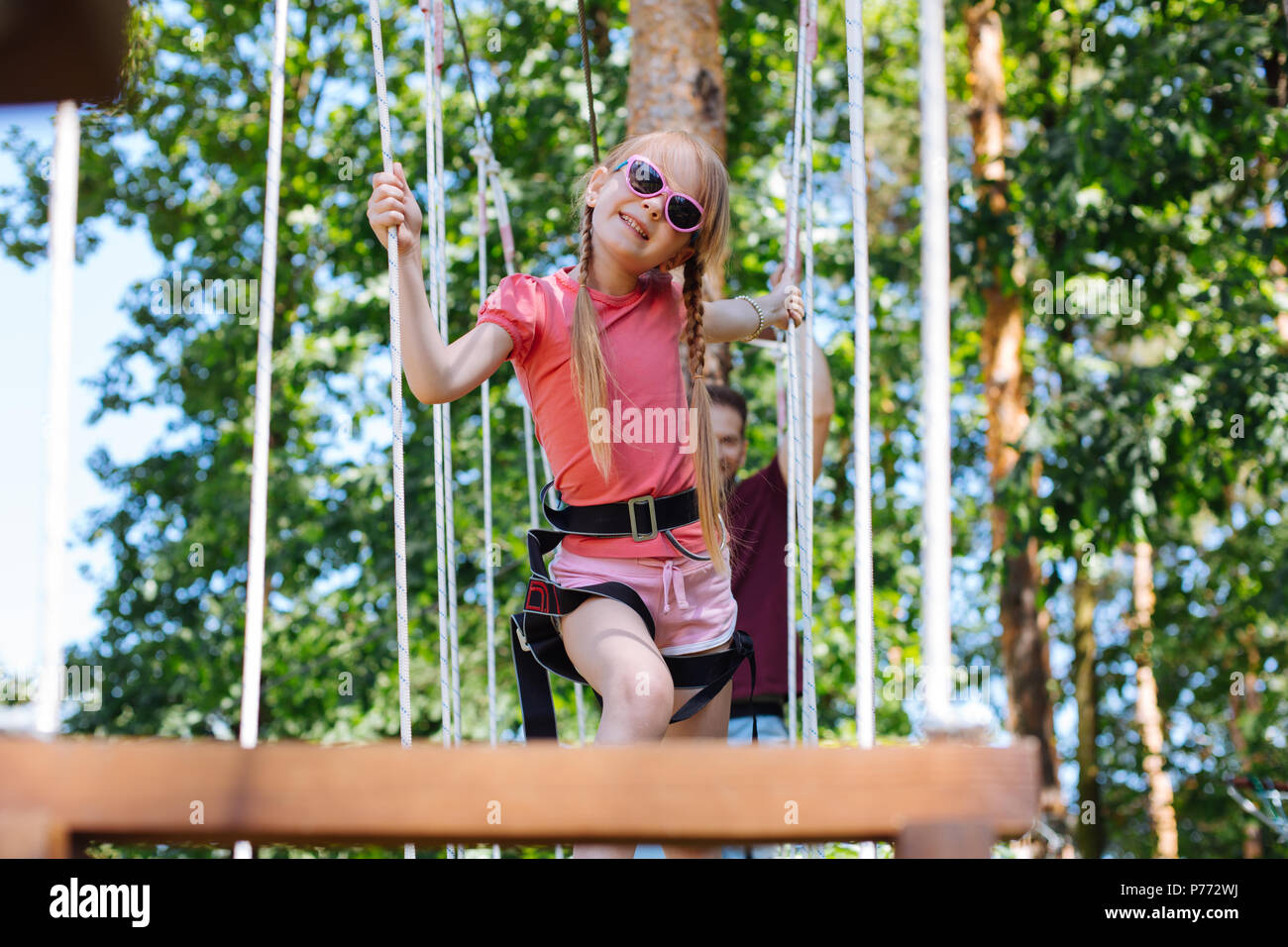 Upbeat little girl posing at a rope park Stock Photo - Alamy