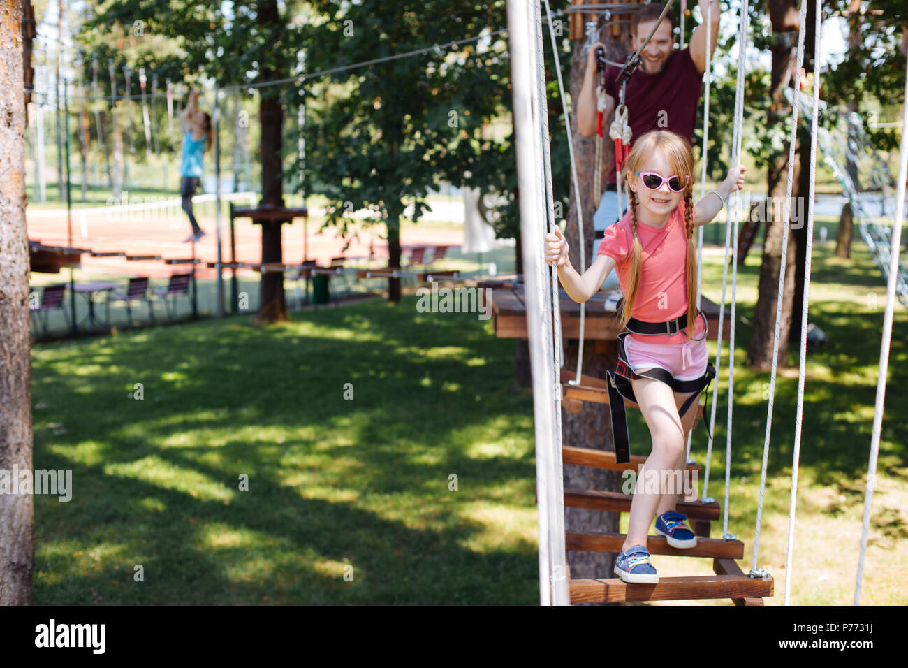 Cheerful little girl going down rope bridge Stock Photo - Alamy