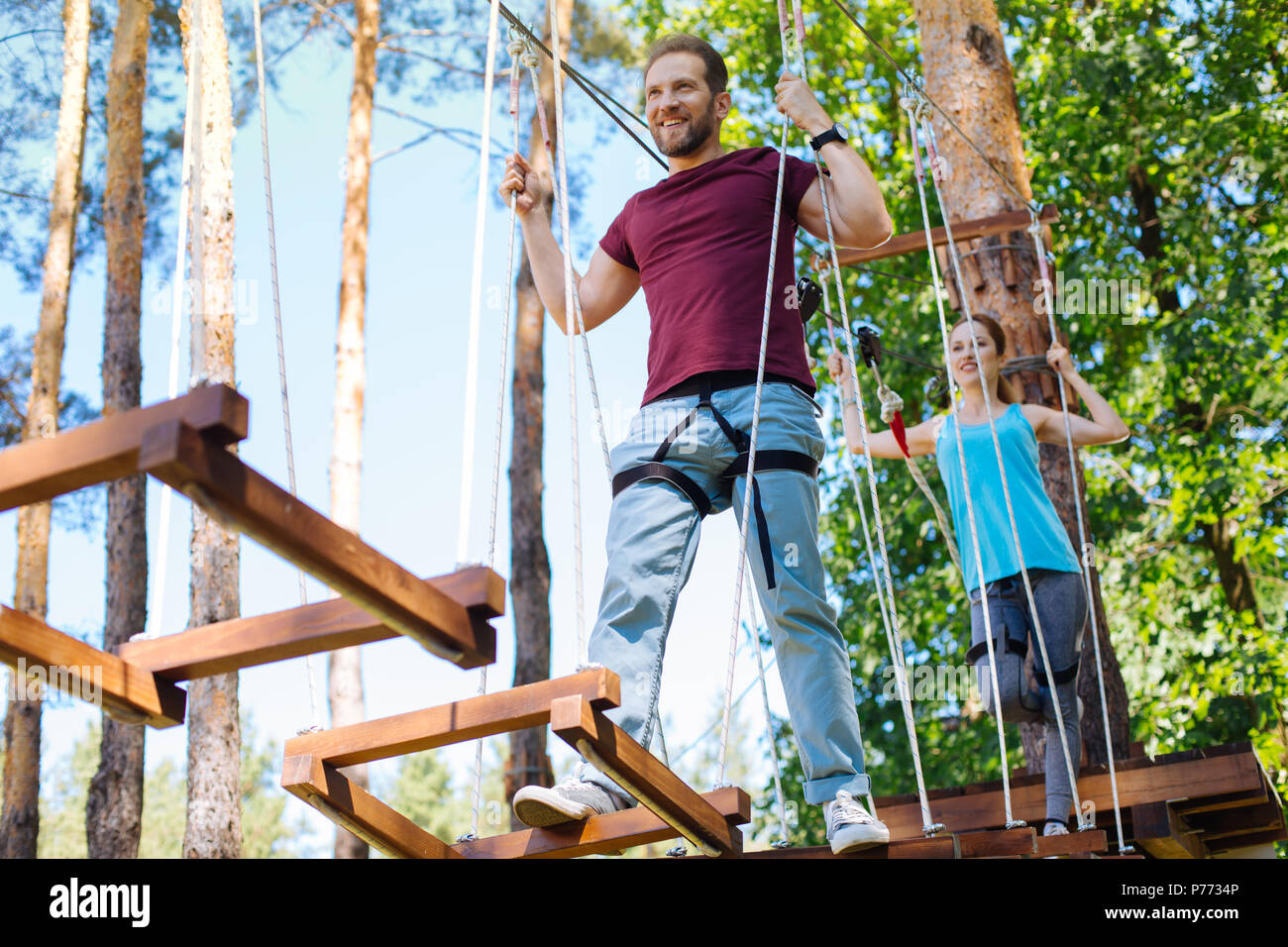 Cheerful young couple climbing at a rope park Stock Photo - Alamy