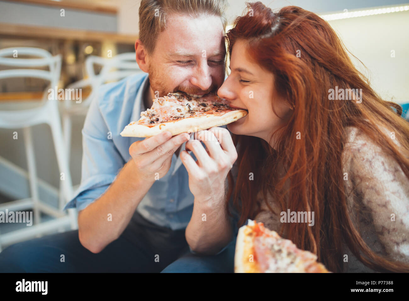 Couple sharing pizza and eating Stock Photo - Alamy