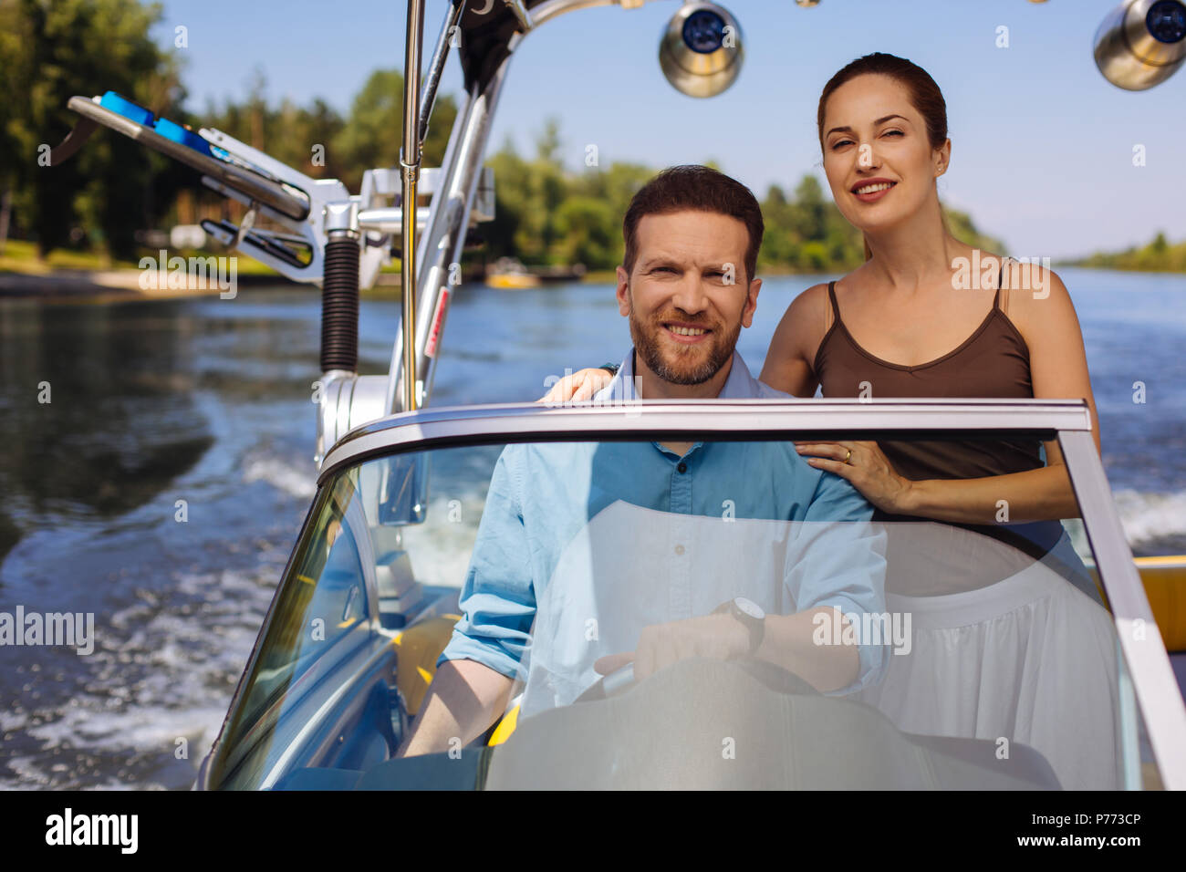 Cheerful young couple smiling while sailing a motorboat Stock Photo - Alamy