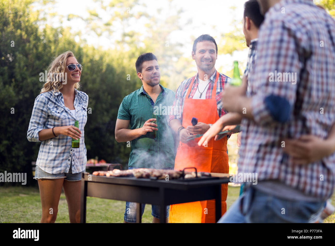 Happy students having barbecue on summer day Stock Photo - Alamy