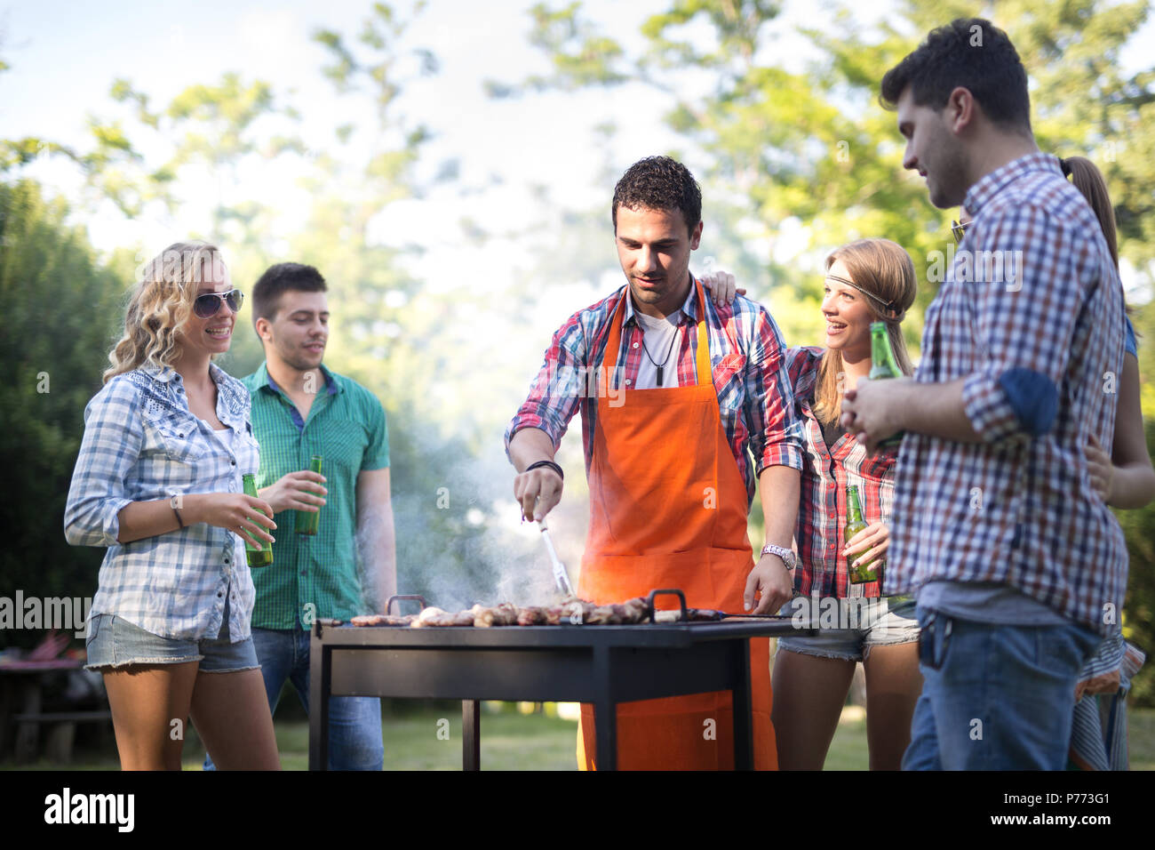 Happy students having barbecue on summer day Stock Photo - Alamy