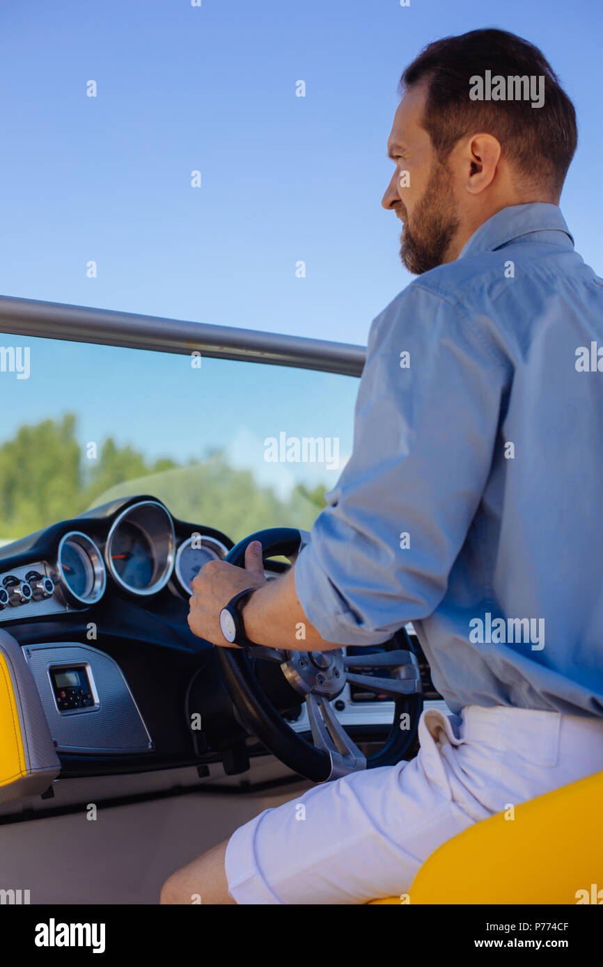 Handsome young man sitting behind a steering wheel of yacht Stock Photo ...