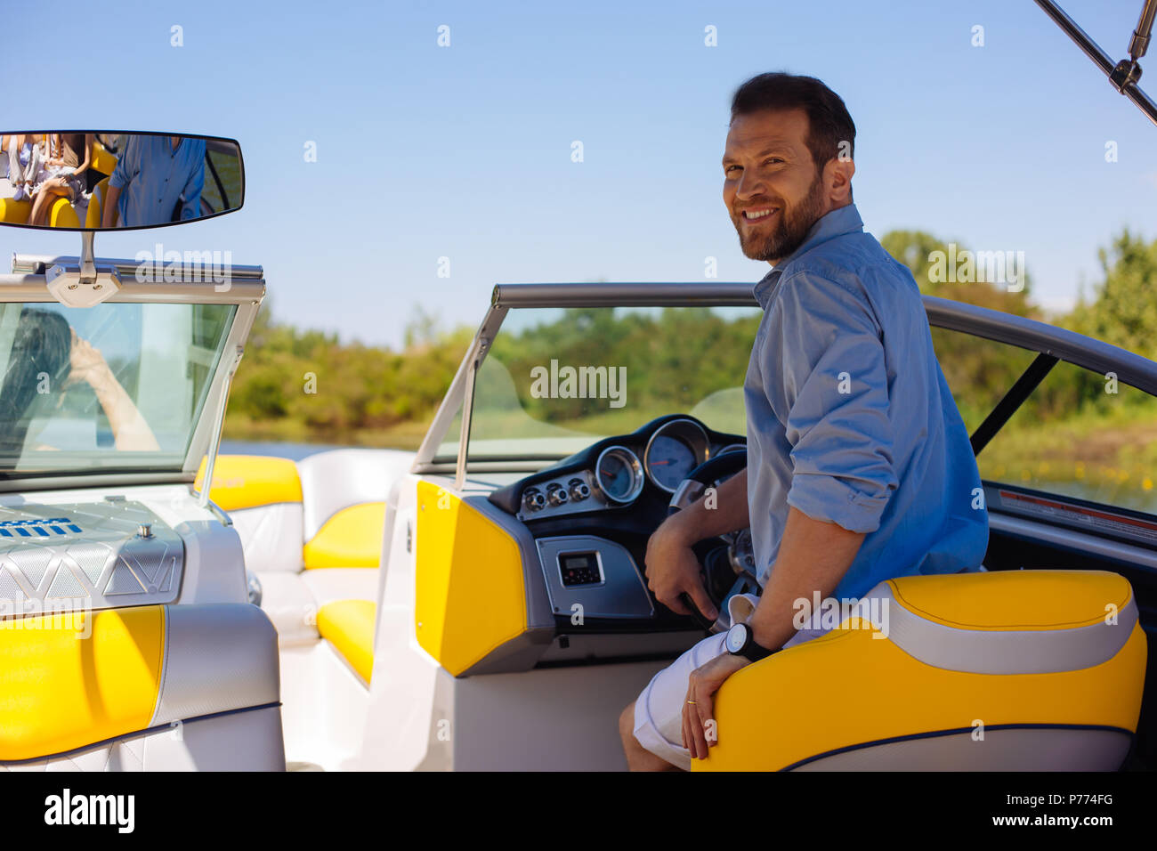 Charming young man posing behind steering wheel of yacht Stock Photo ...