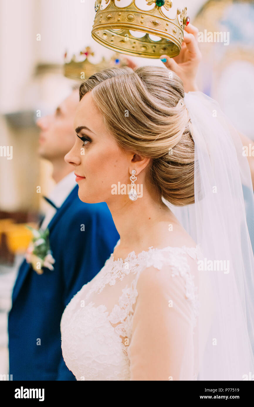 The golden crown under the bride`s head during the wedding ceremony ...