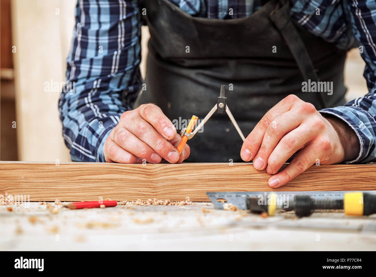 A close up of a male carpenter marks of a metal compass and a pencil on ...