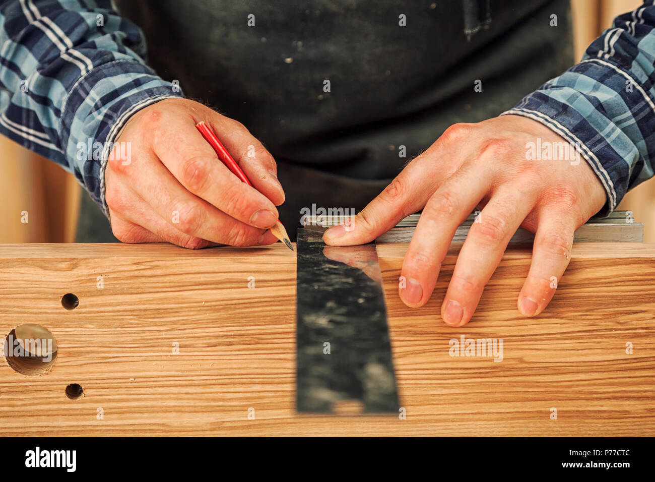 Close-up The man measures a wooden board with a ruler and marks with ...