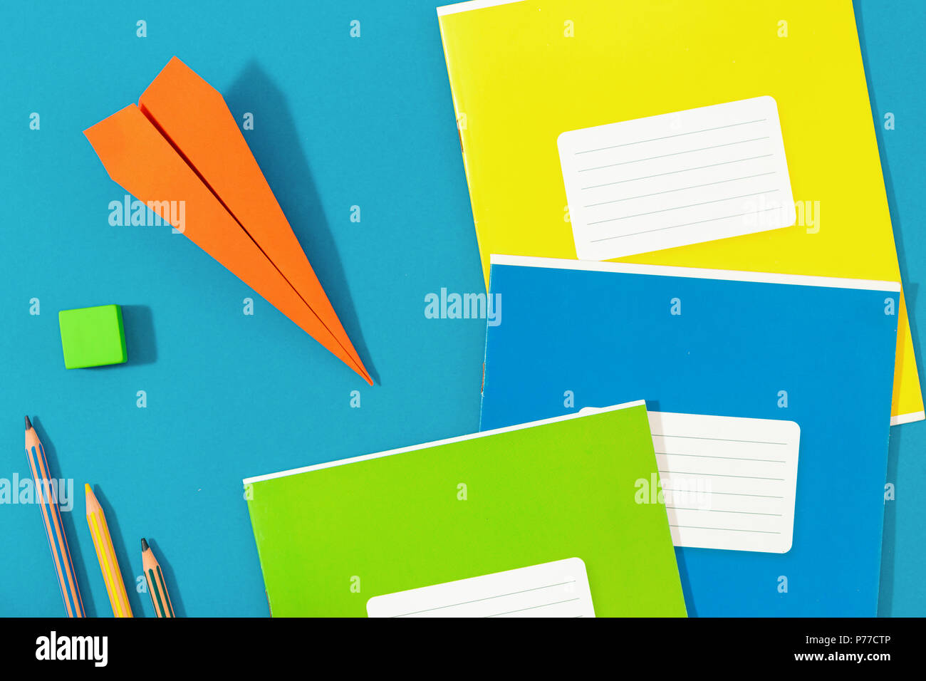 Flat lay paper airplane with school supplies on blue background. Top ...