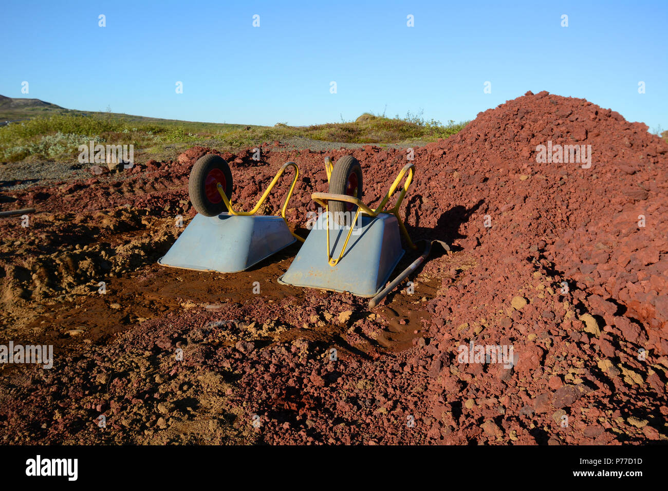Blue and Yellow Wheelbarrows In Red Soil Stock Photo - Alamy