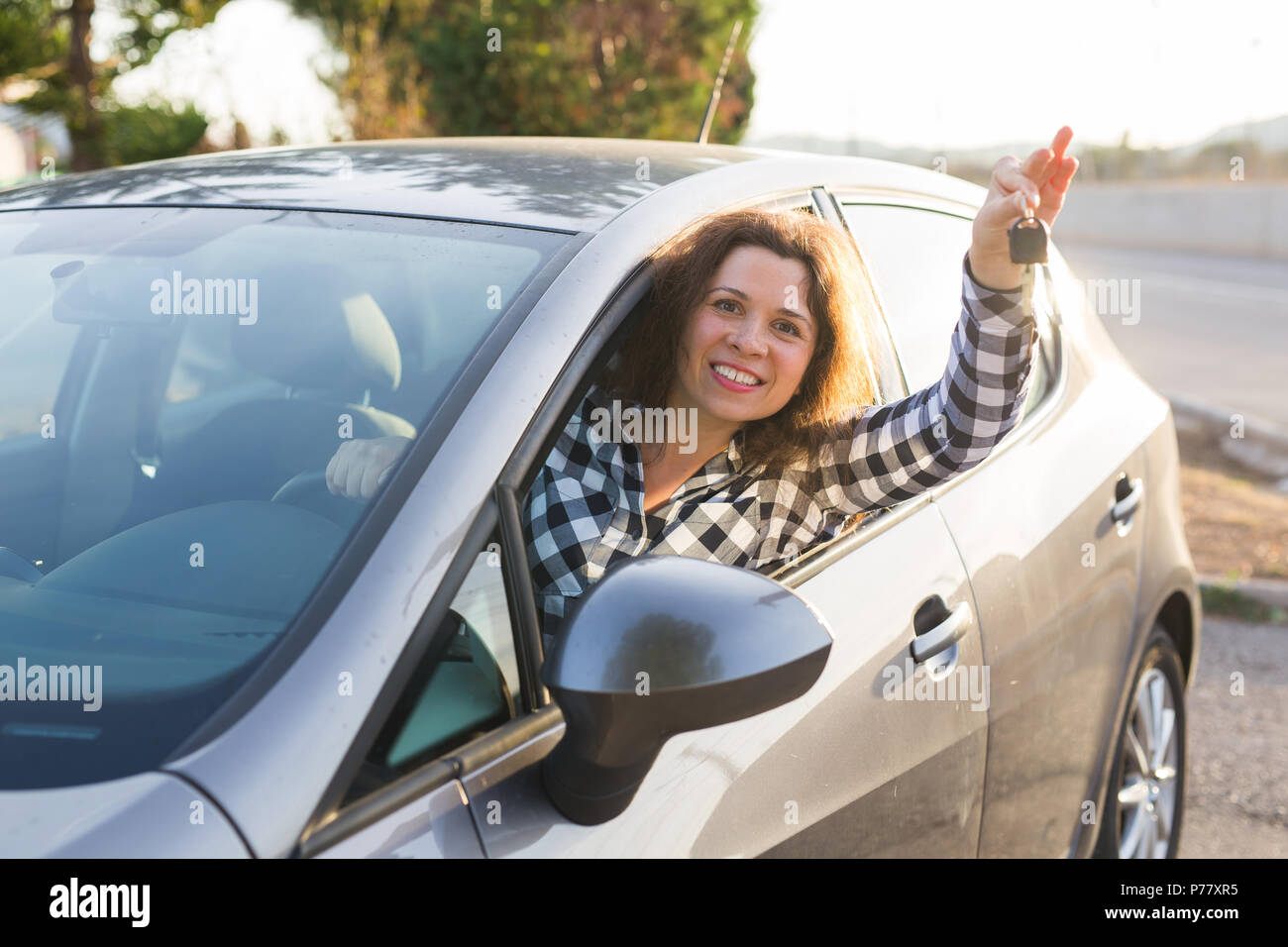 European woman behind the car wheel showing car key Stock Photo - Alamy
