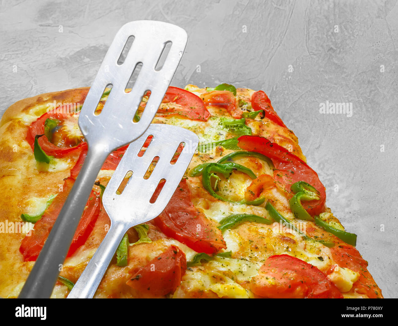 Fresh baked piece of pizza and tongs on the top, on grey background ...