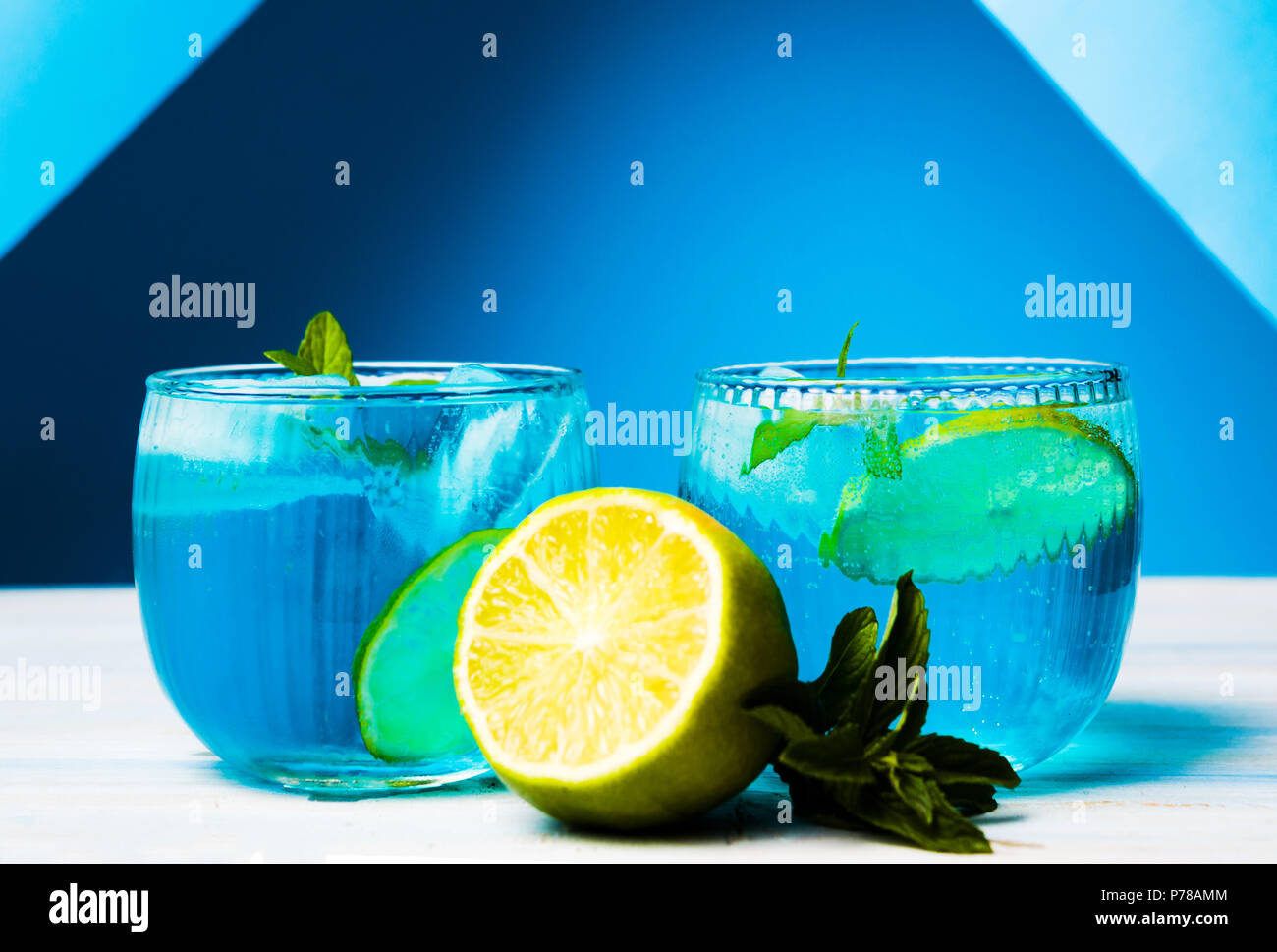 Blue cocktails decorated with lemon on matching background Stock Photo ...