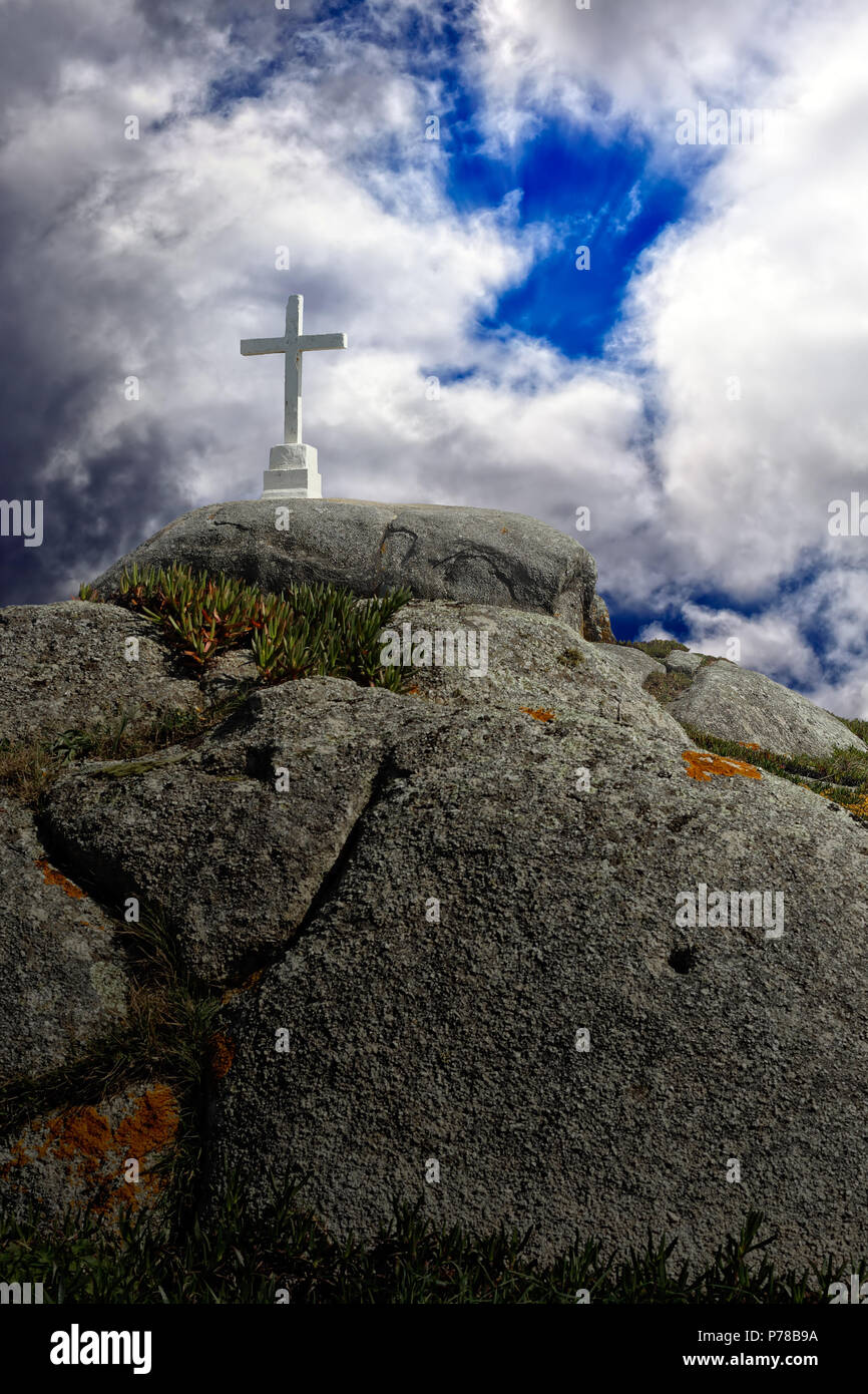 Stone cross on a hill (big cliff) against an enhanced dramatic sky ...