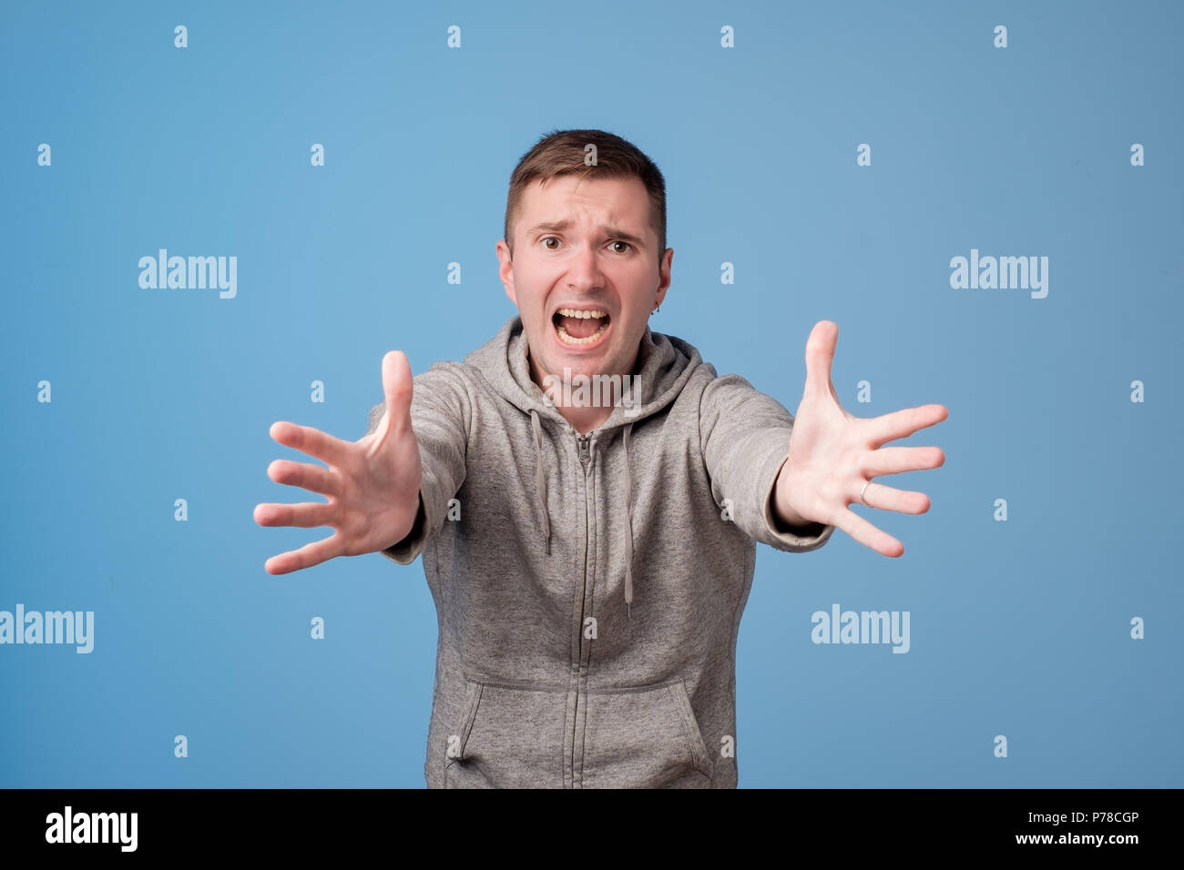 Studio portrait of european man pulling his hands ahead Stock Photo - Alamy
