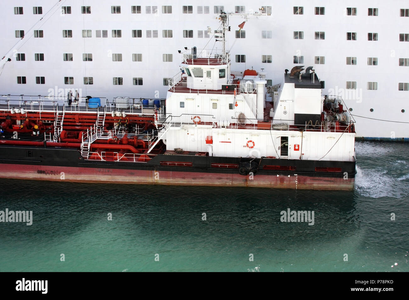 Delivering ship refueling big white passenger cruise liner. Refueling ...