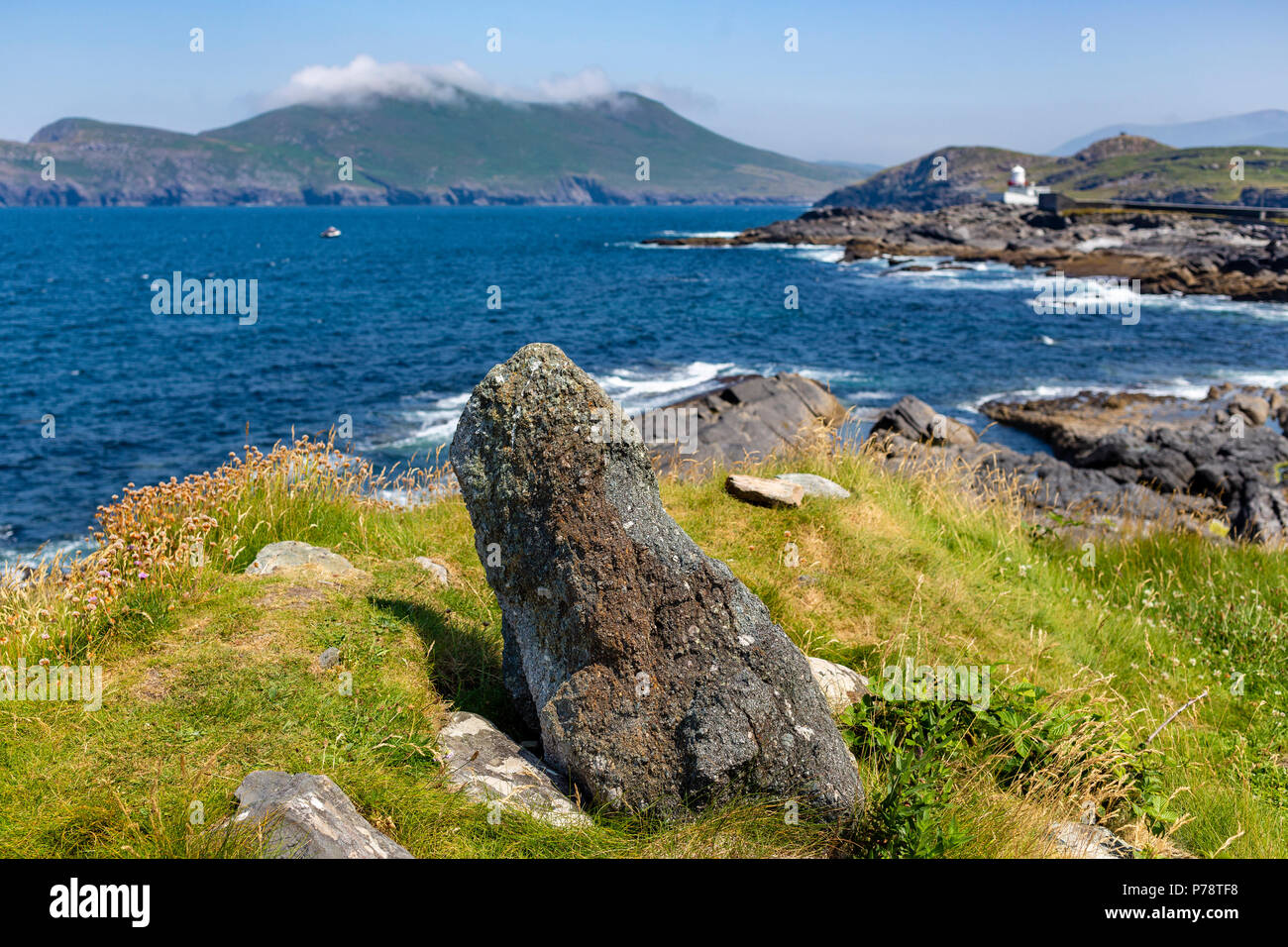 Small standing stone and Valentia Island lighthouse in the background ...
