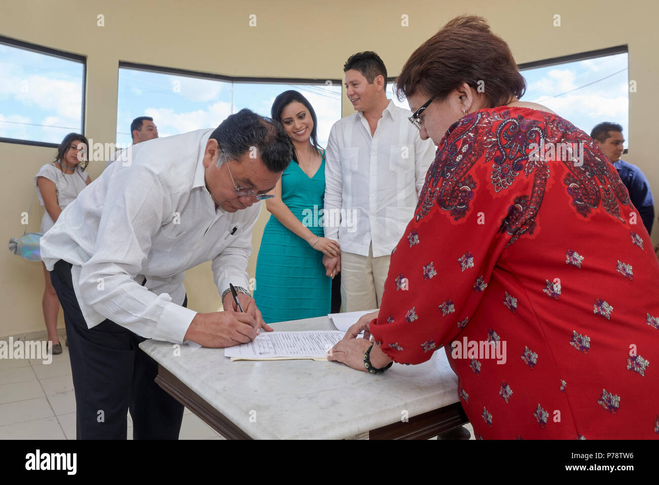 Witness signing the marriage registry document during a young couple's ...
