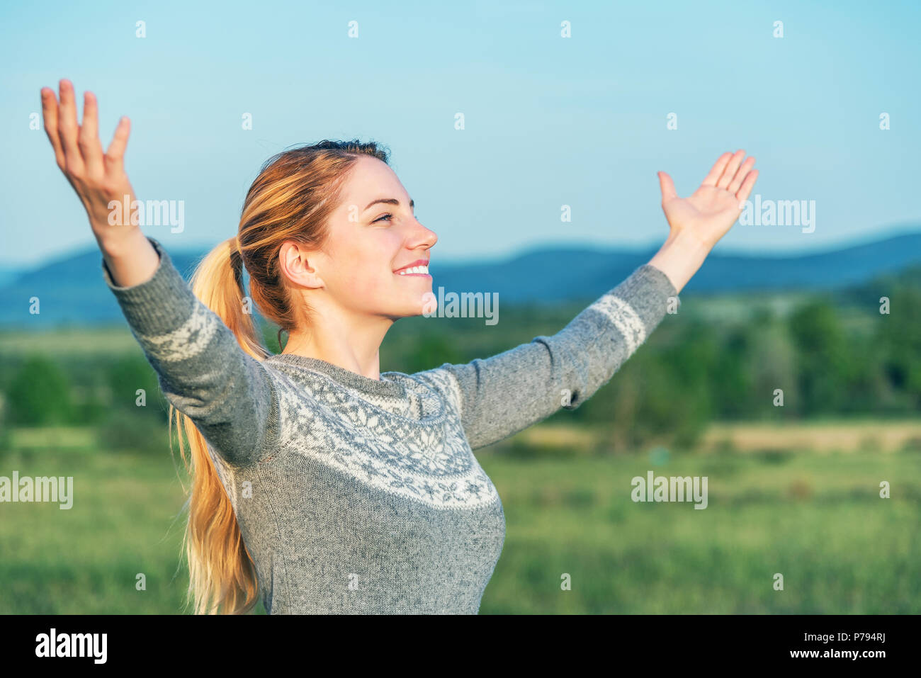 Woman with hands raised in nature Stock Photo - Alamy