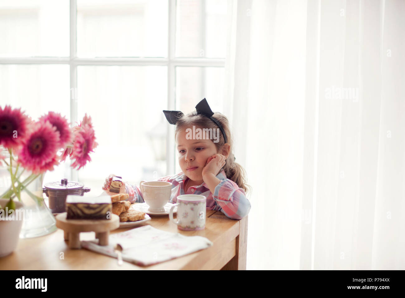 A little girl at the table is eating breakfast by the window. Good ...