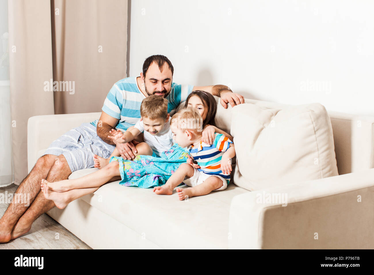 Man with his children sitting on the white sofa Stock Photo - Alamy