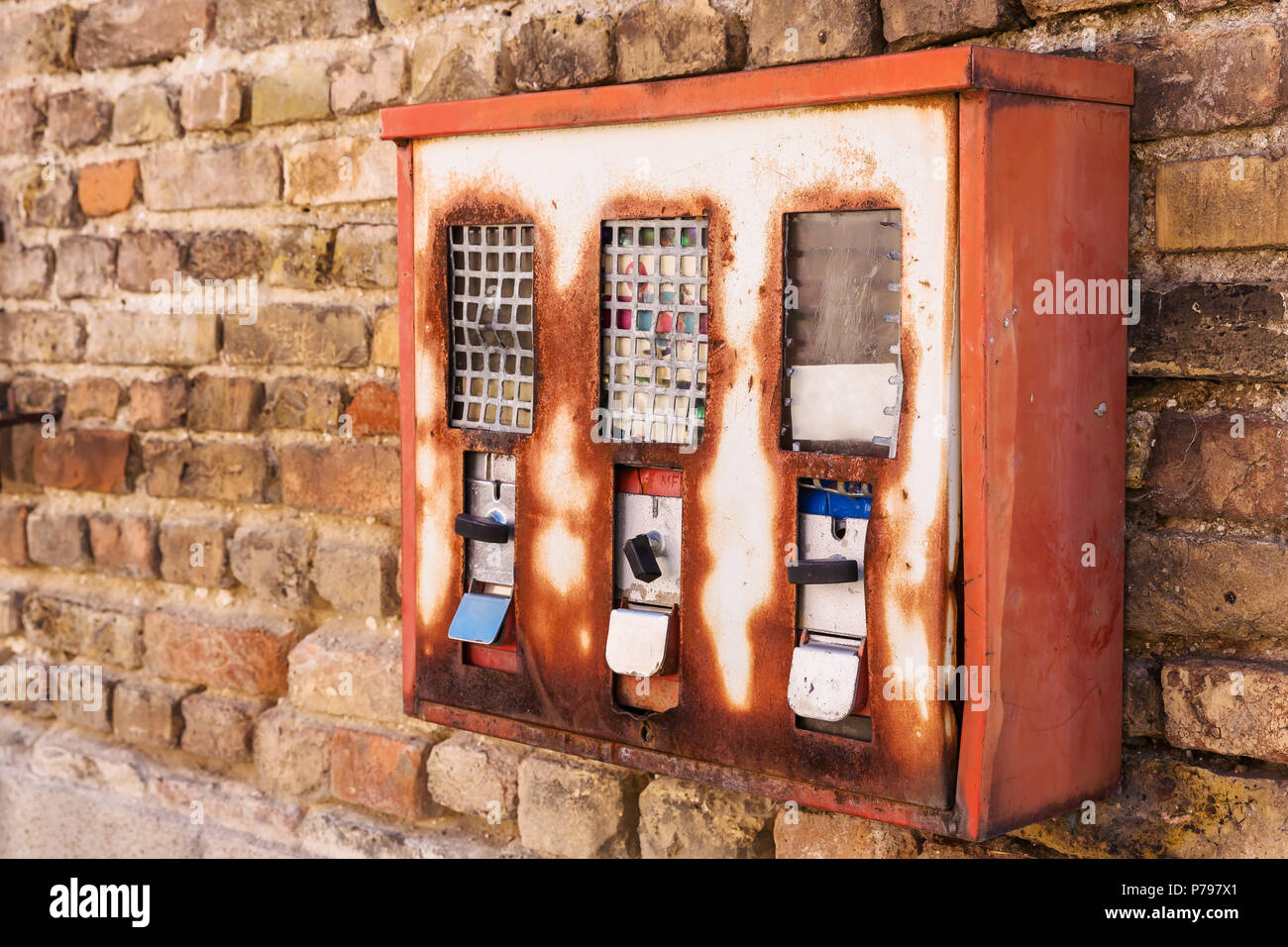 picture of a rusted, antique gumball machine at a brick wall Stock ...