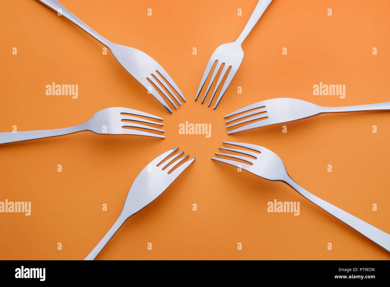 Six forks laying on orange background Stock Photo - Alamy