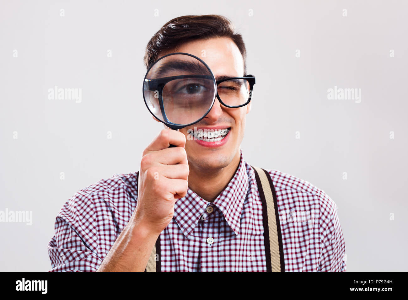 Nerd looking with loupe Stock Photo - Alamy