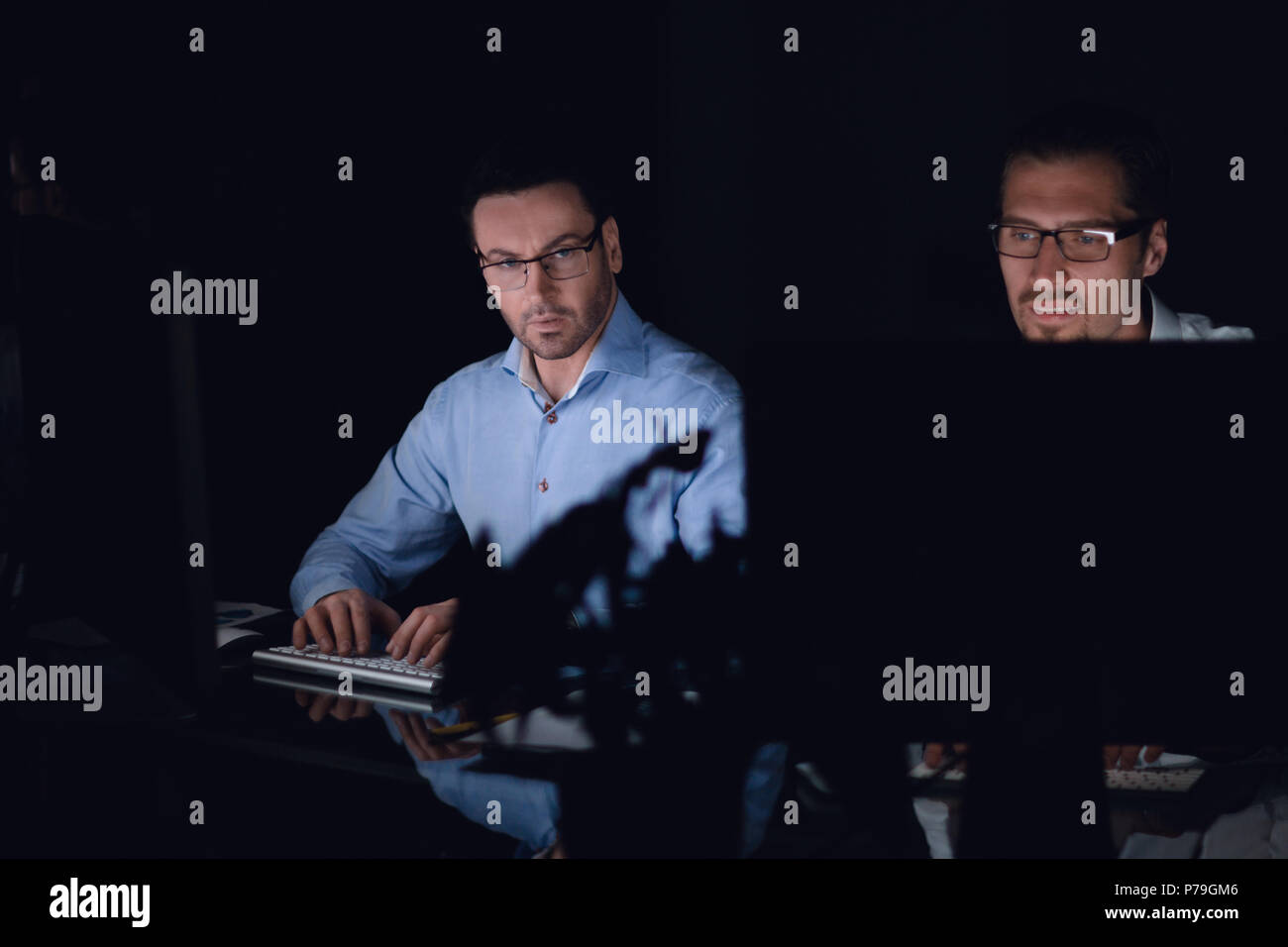 close up.employees work on computers in a dark office Stock Photo - Alamy