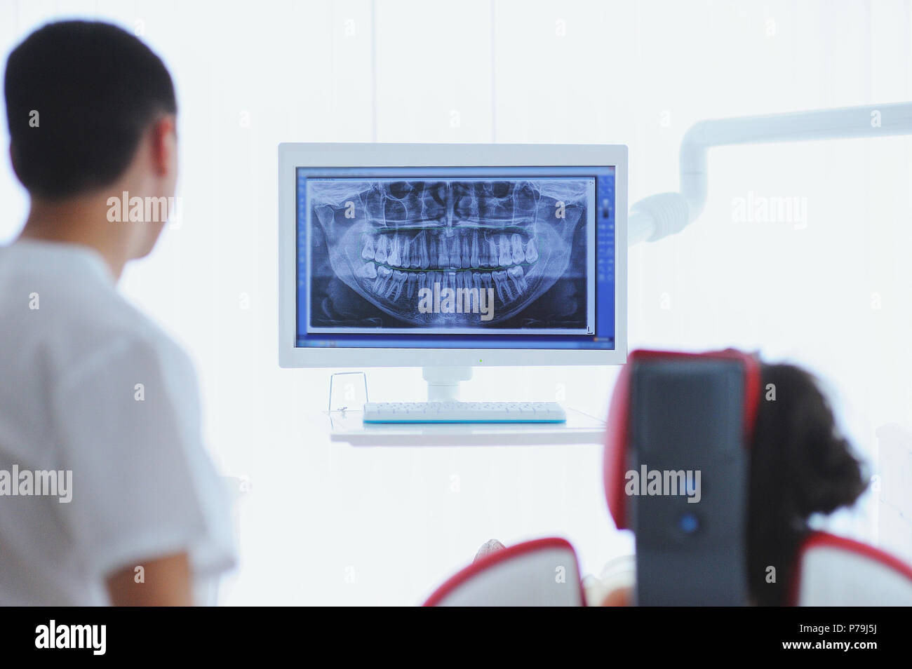 A dentist shows the young patient an X-ray of the teeth on the monitor ...