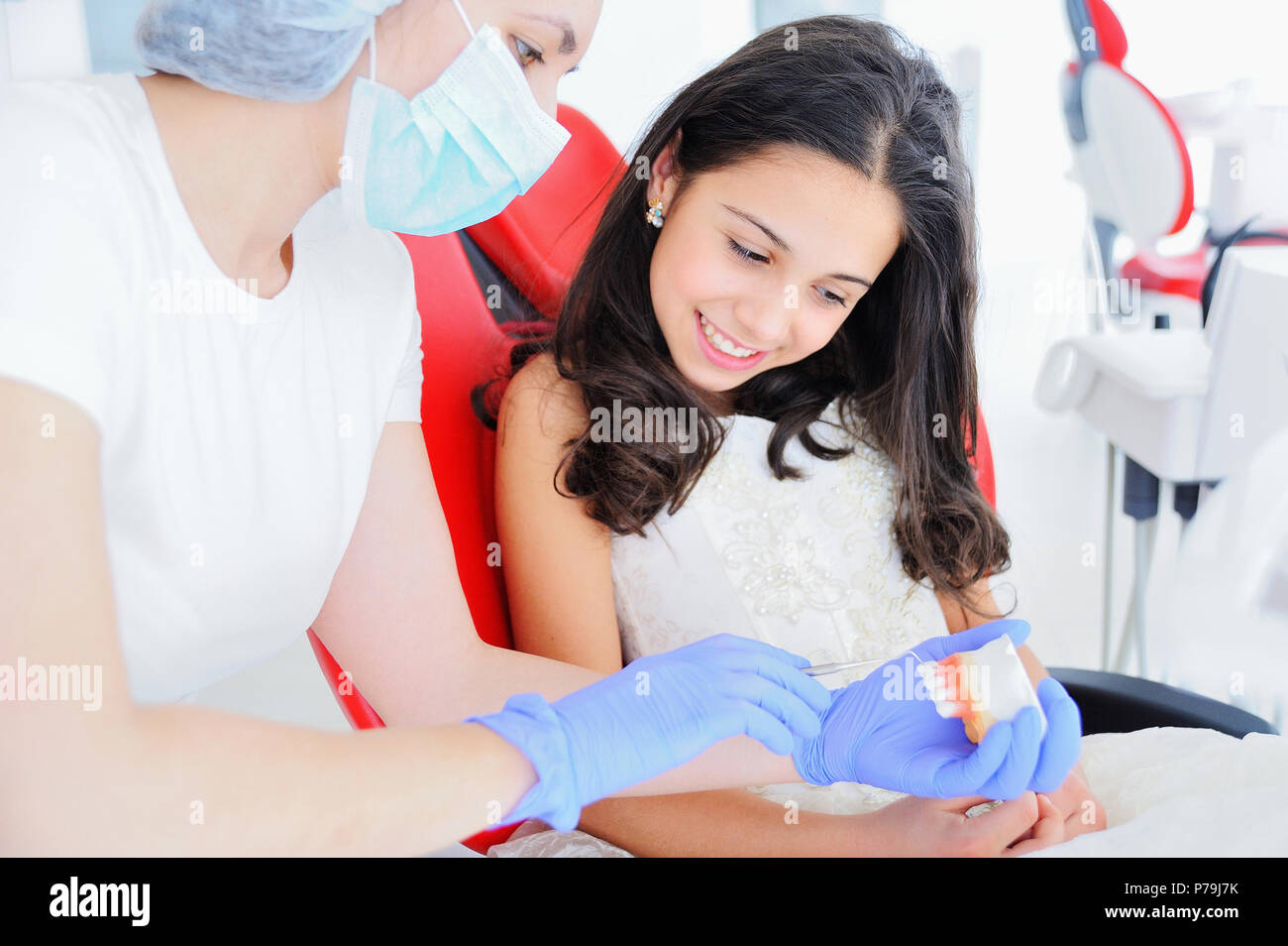 Young girl dentist in mask shows young beautiful girl dentures Stock ...