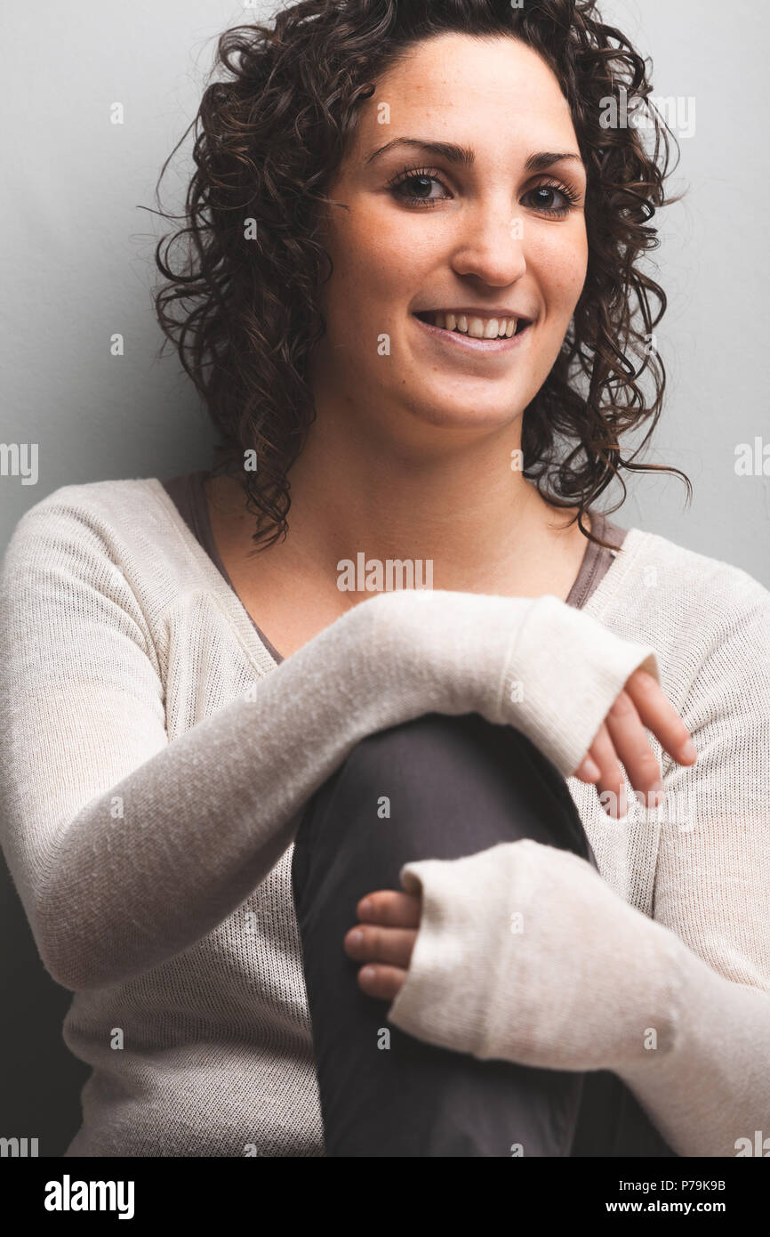 portrait of a natural curly woman smiling with her arm on her knee ...