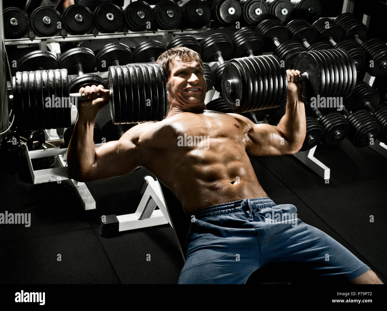 very power athletic guy , execute exercise press with dumbbells ...
