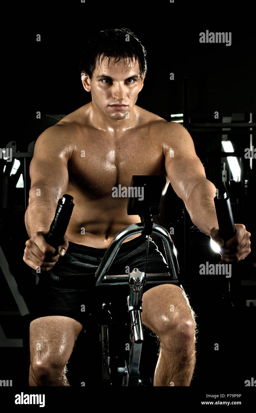 bodybuilder guy , workout on exercise bicycle, on dark background Stock ...