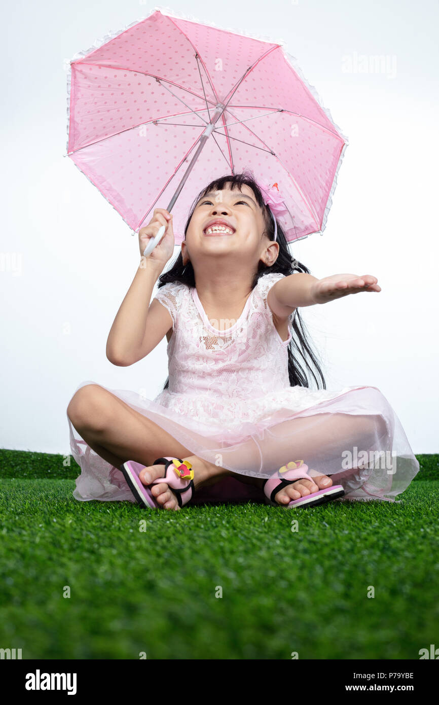 Asian Little Chinese Girl holding umbrella and sitting on the grassland ...