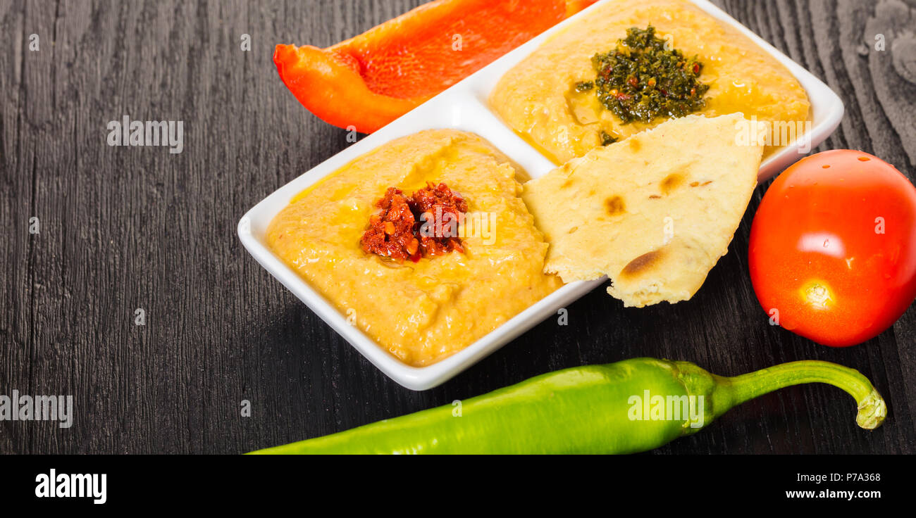 hummus with vegetables on a black wooden background Stock Photo - Alamy