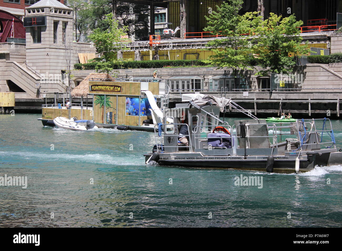 Trash management boat sailing past a party boat along the Chicago River ...