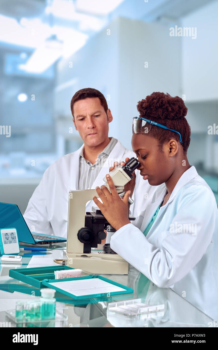 Scientists, senior Caucasian male and young African female, work with a ...