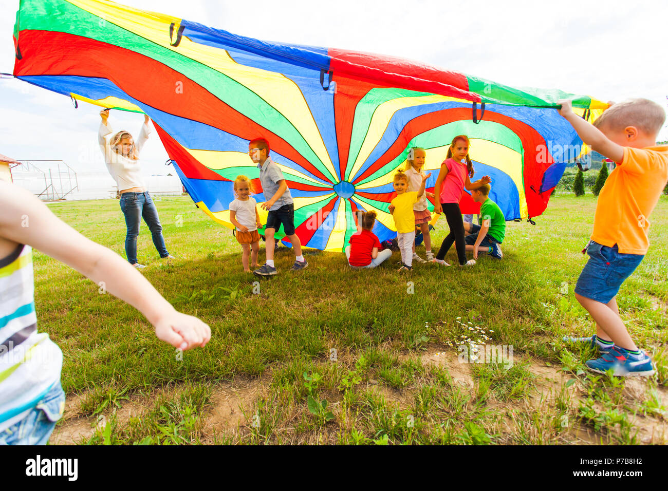 Happy kids waving rainbow parachute Stock Photo - Alamy