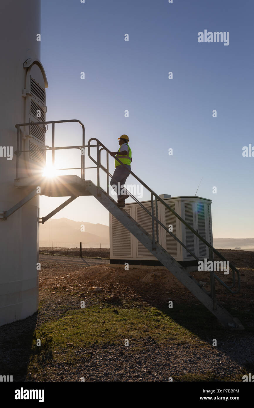 Engineer climbing up the stairs of a wind mill Stock Photo - Alamy