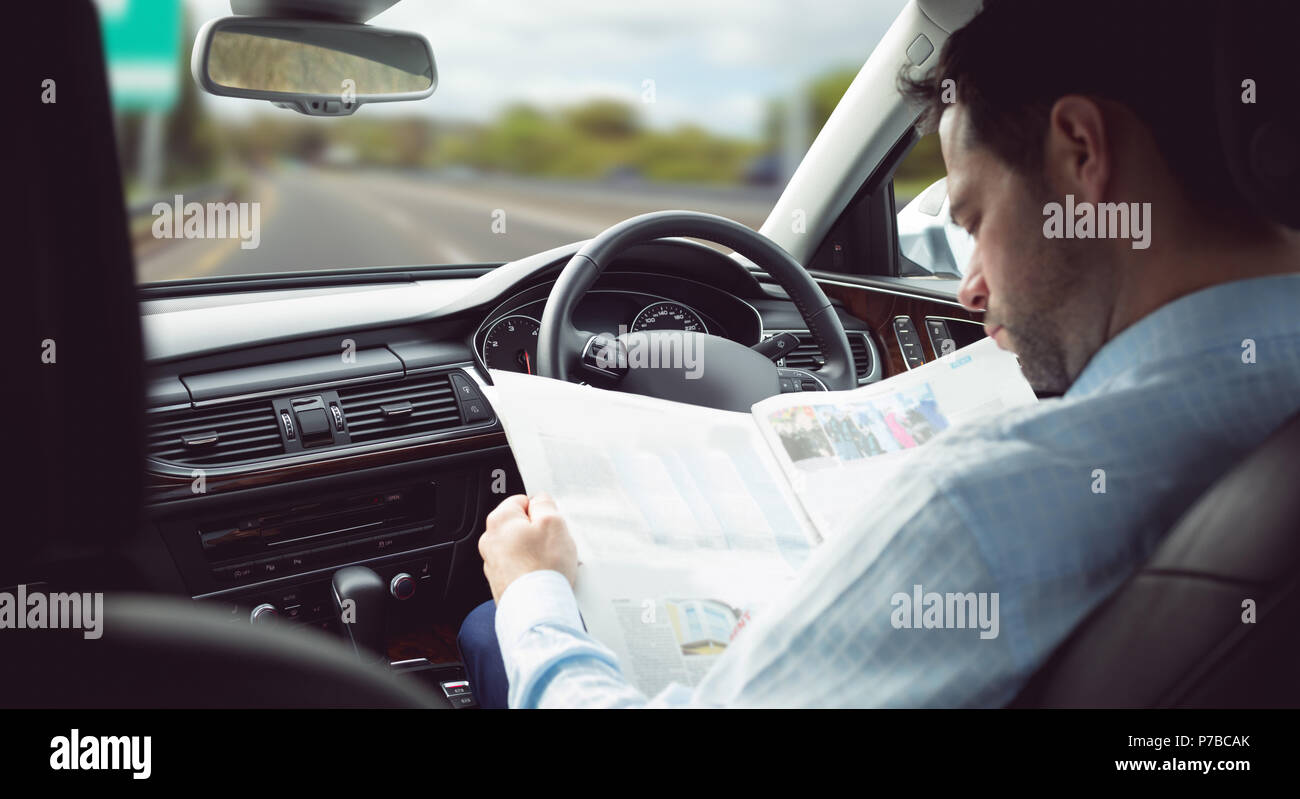 Businessman reading newspaper in a car Stock Photo - Alamy