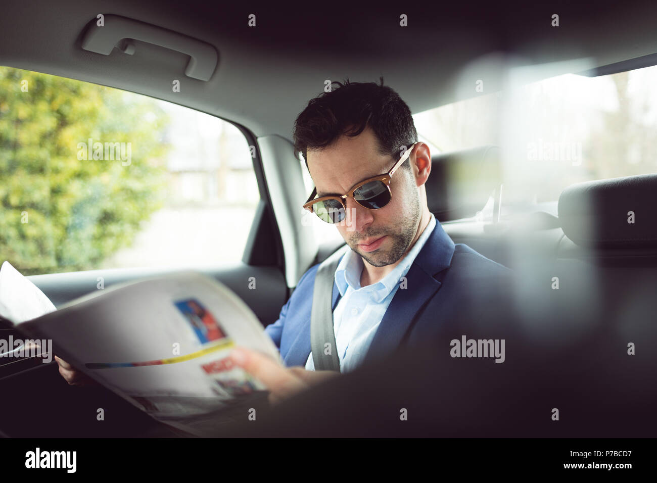 Businessman reading newspaper in a car Stock Photo - Alamy