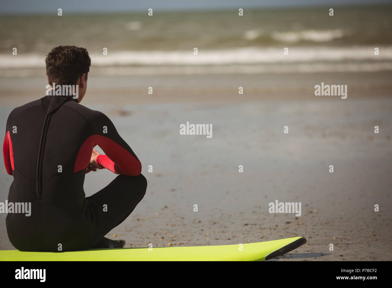 Surfer sitting on the surfboard on beach Stock Photo - Alamy