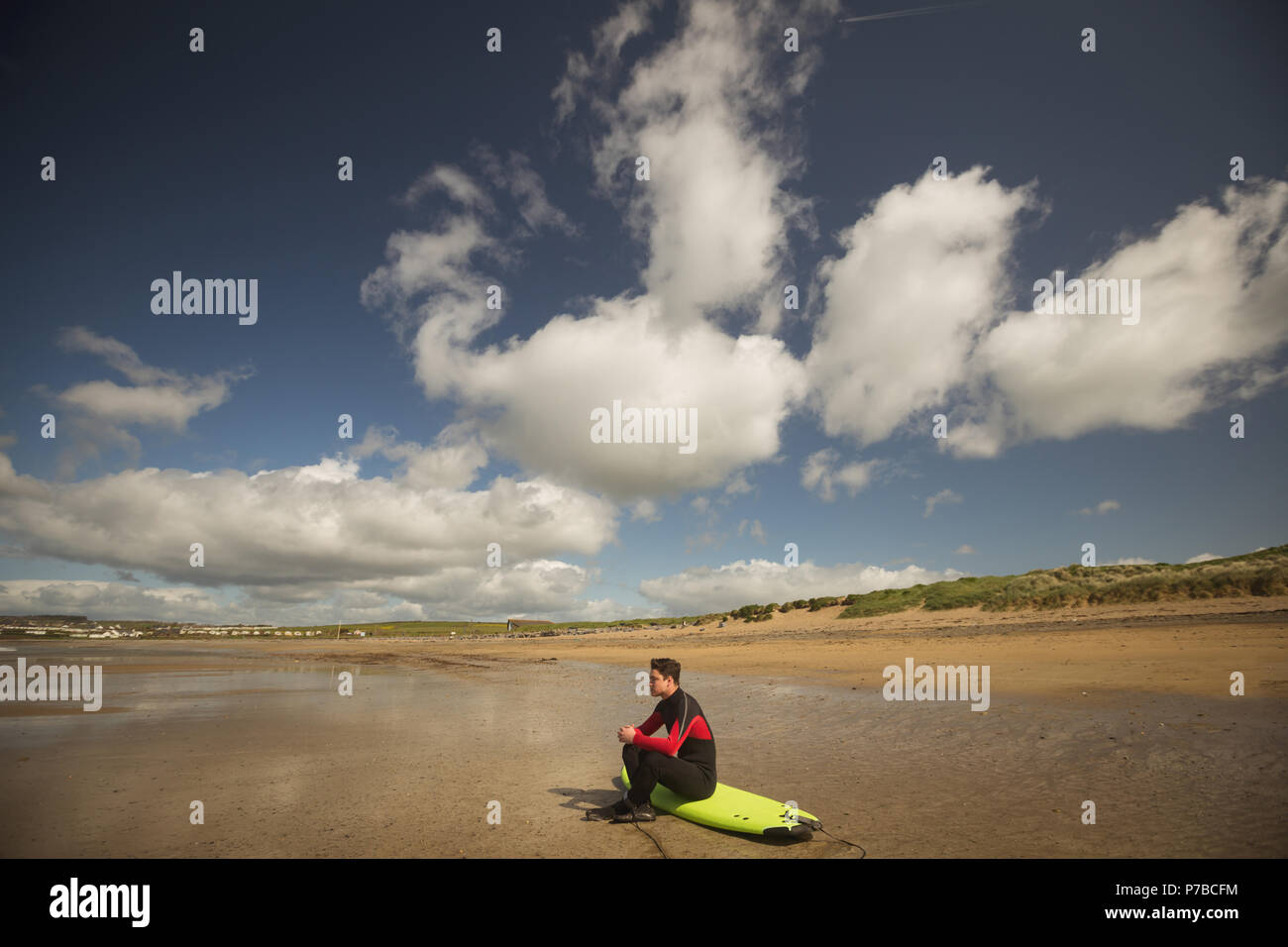 Surfer sitting on the surfboard and looking at sea Stock Photo - Alamy