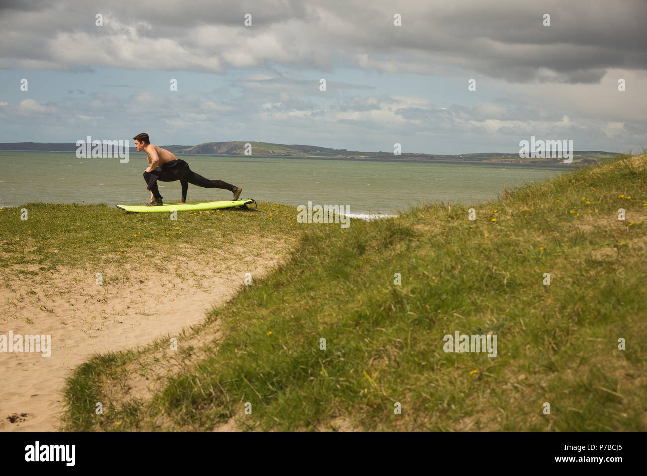 Surfer with surfboard performing stretching exercise at beach Stock ...