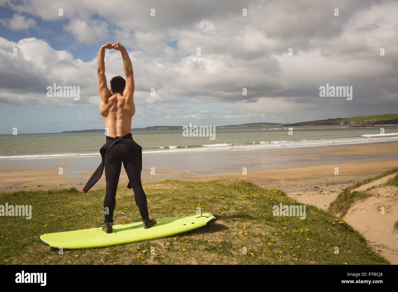 Surfer with surfboard performing stretching exercise at beach Stock ...