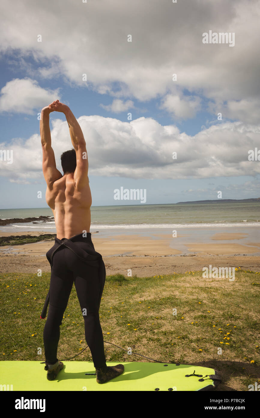 Surfer with surfboard performing stretching exercise at beach Stock ...